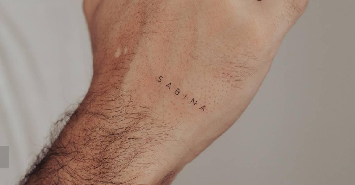 "Sabina" lettering tattoo located on the hand.
