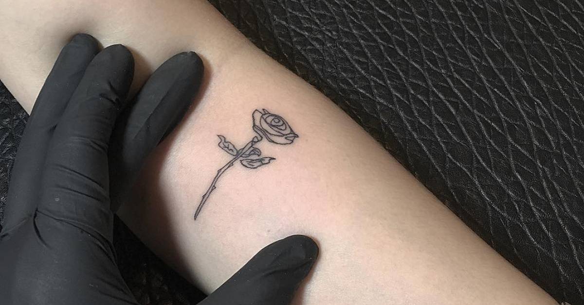 One line rose tattoo located on the inner forearm.