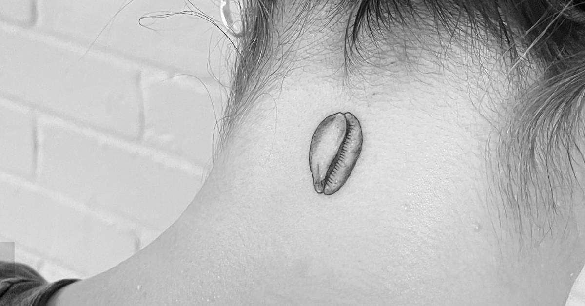 Tiny cowrie shell tattoo done on the back of the neck.
