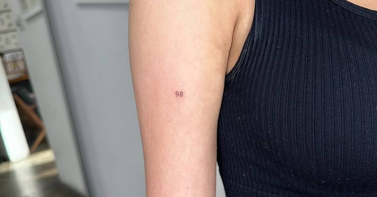 Tiny tattoo of the number "98" located on the bicep.