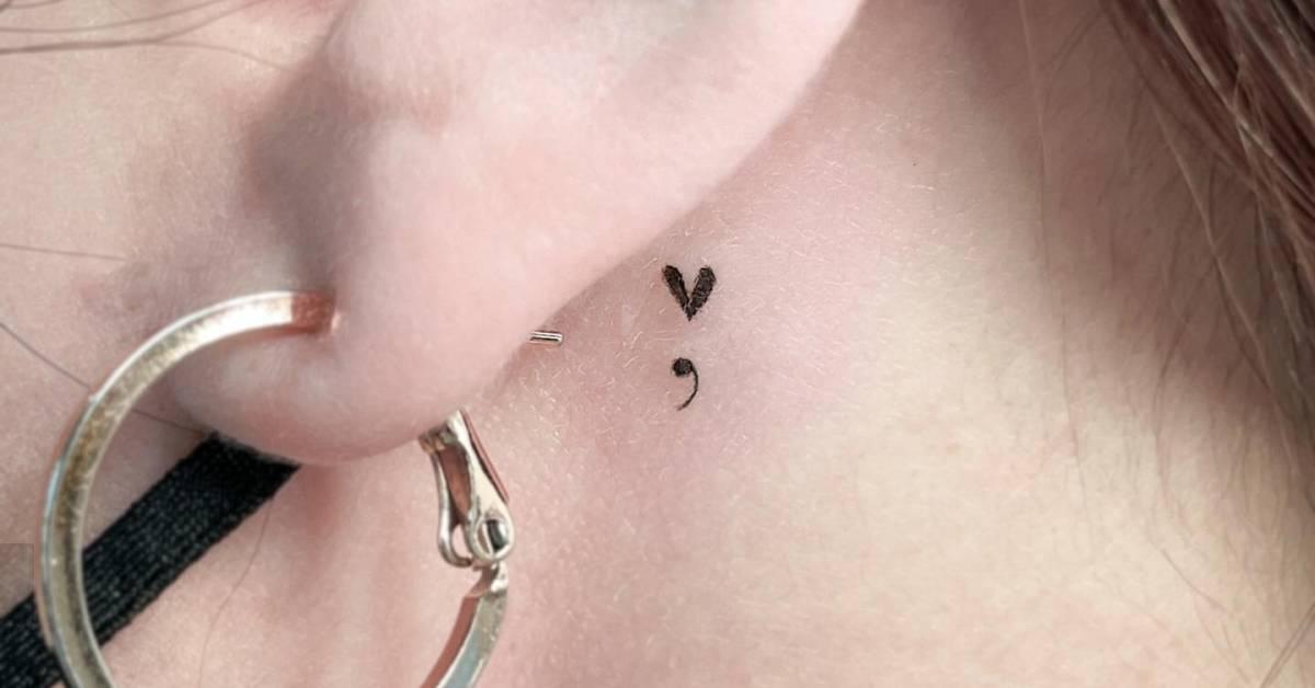 Heart semicolon tattoo placed behind the ear, done in