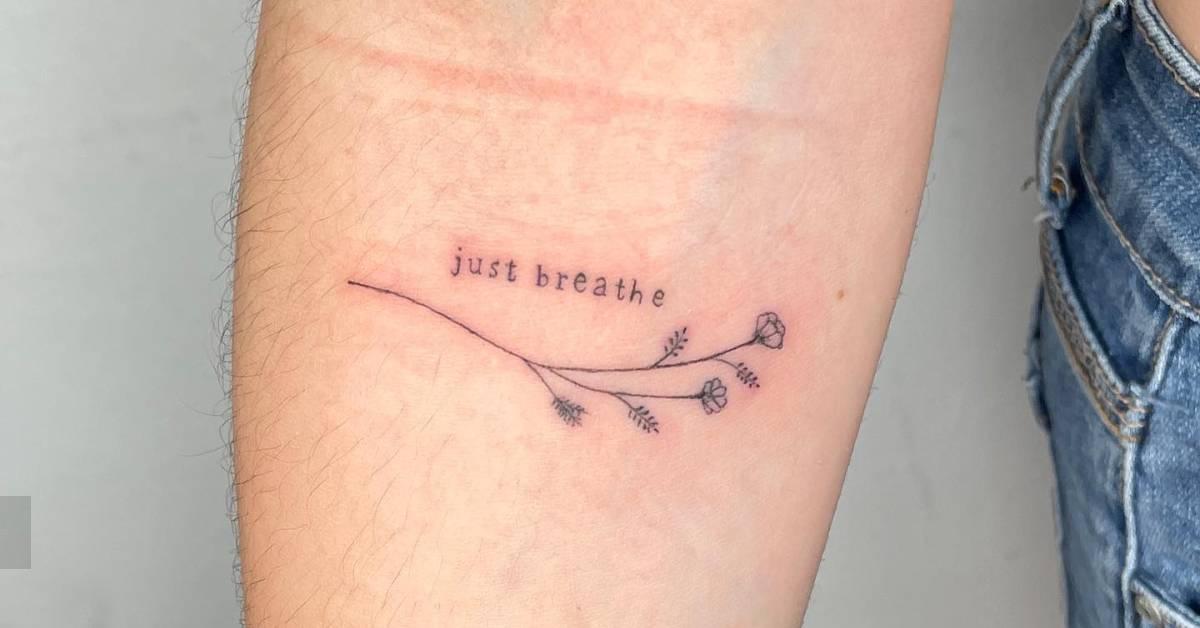 "Just breathe" and flowers tattoo located on the inner