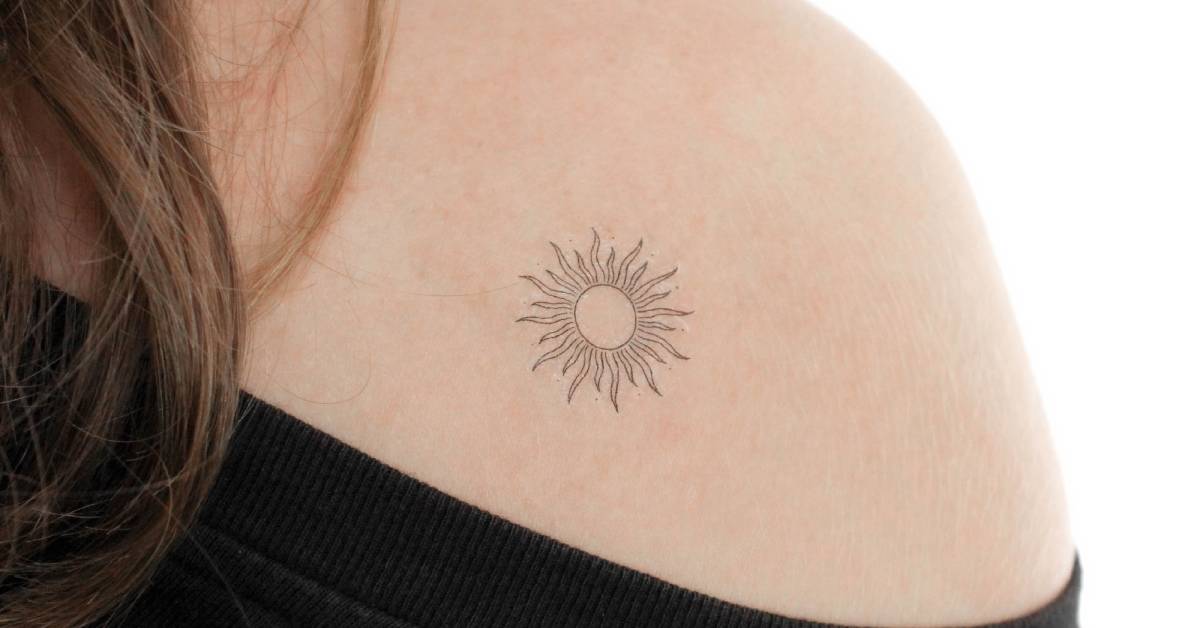 Fine line style shining sun temporary tattoo located on