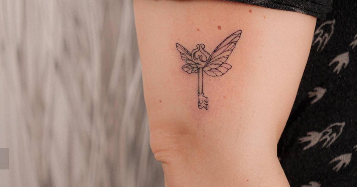 Winged Key tattoo located on the upper arm.