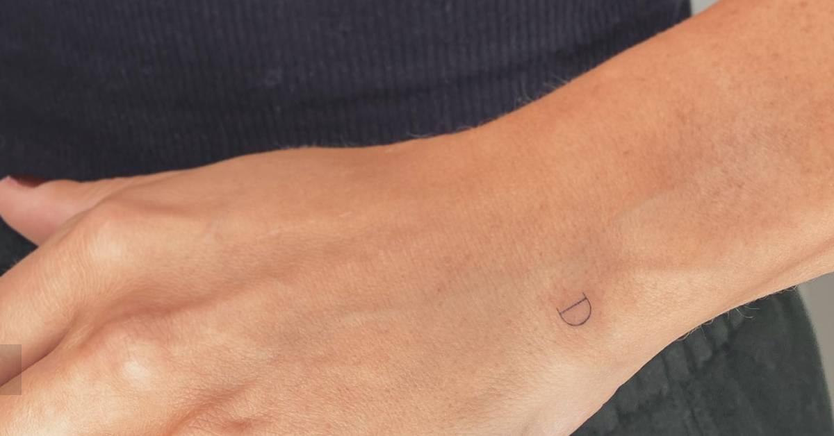 Tiny letter "D" tattoo located on the wrist.
