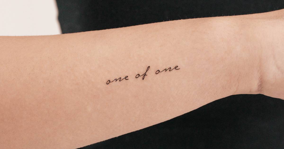 "One of one" temporary lettering tattoo located on the