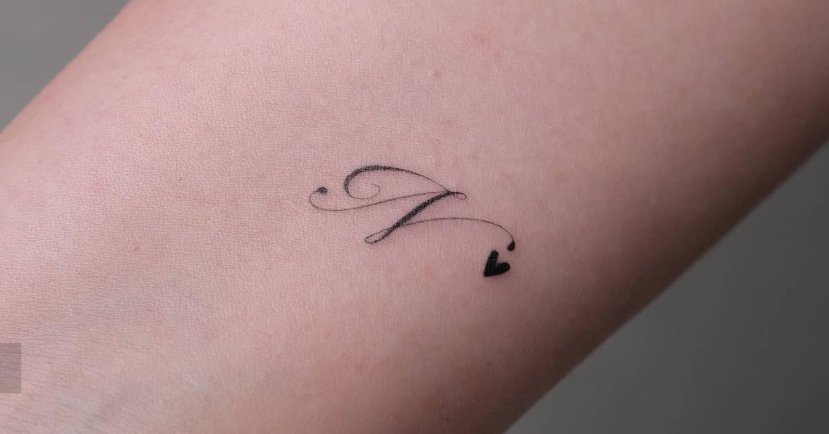 Letter "N" and tiny heart tattoo located on the wrist.