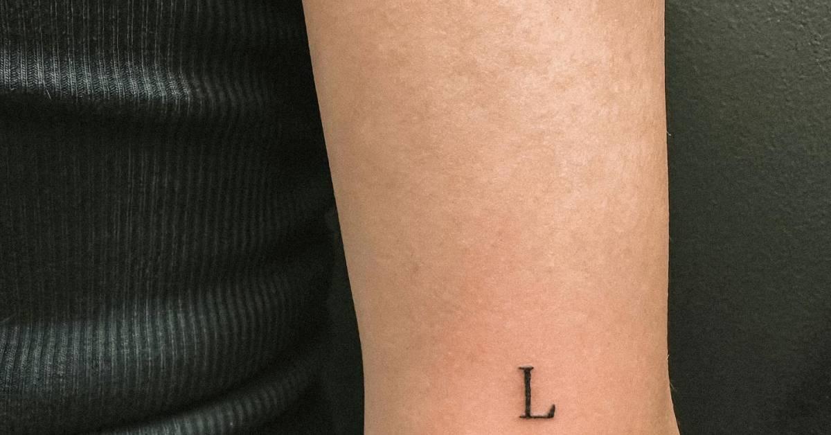 Tiny minimalistic letter "L" tattoo done on the tricep.