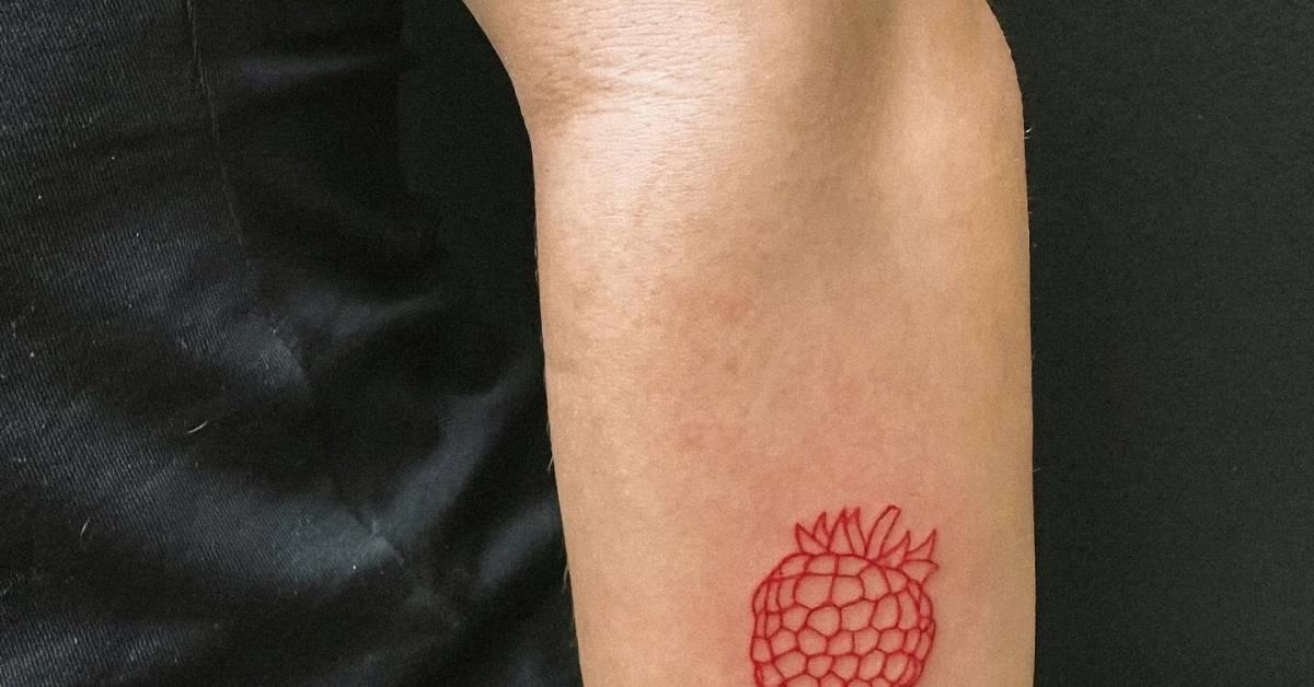 Fine line style raspberry tattoo in red ink located on