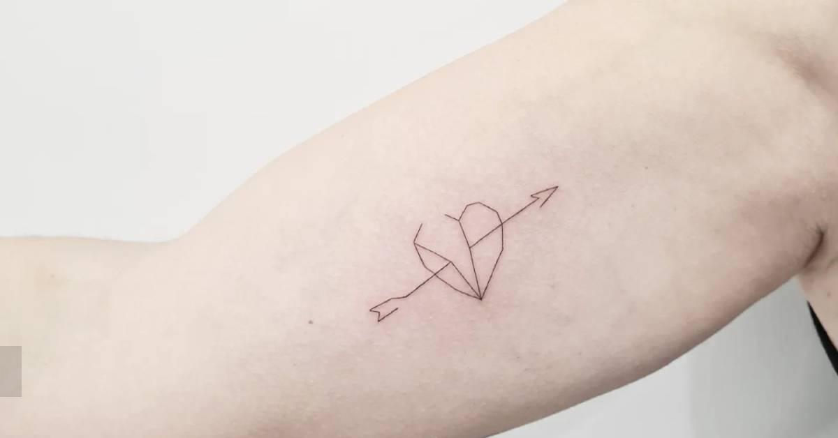 Fine line style heart and arrow tattoo placed on the