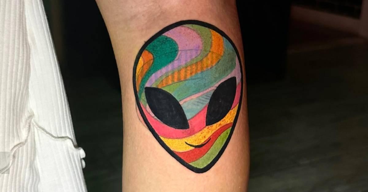 Colorful alien head tattoo located on the calf.