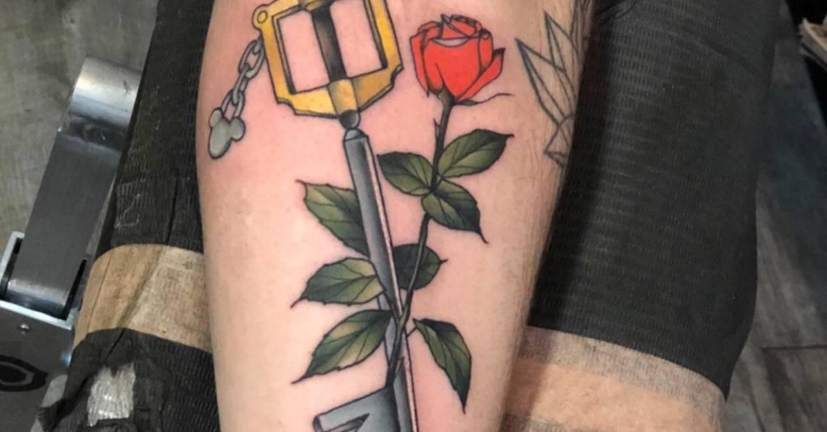 Key and red rose tattoo located on the forearm,