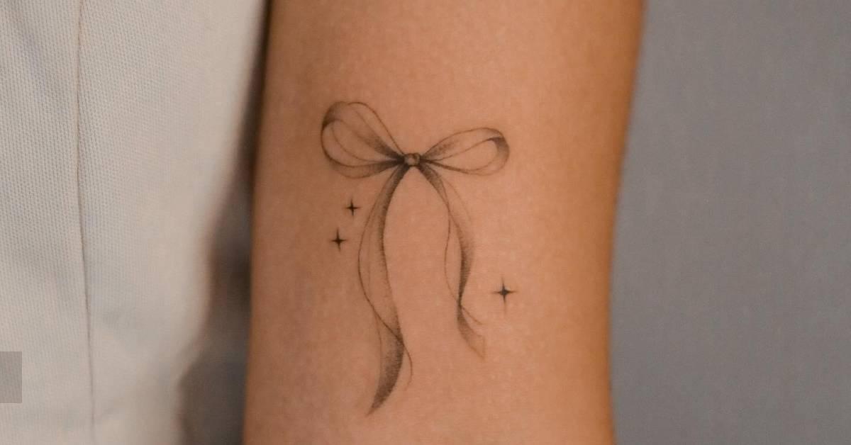 Illustrative style ribbon tattoo located on the bicep.