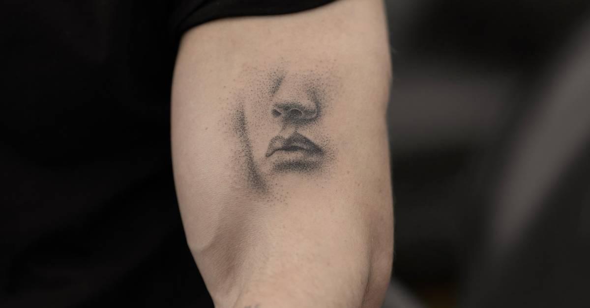 Dotwork style face tattoo located on the upper arm.