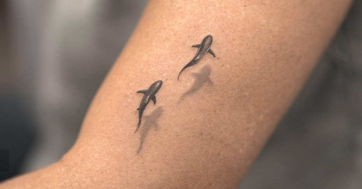 Little swimming sharks tattooed on the upper arm.