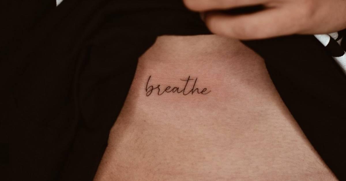 Lettering tattoo of the word "breathe" handwritten on