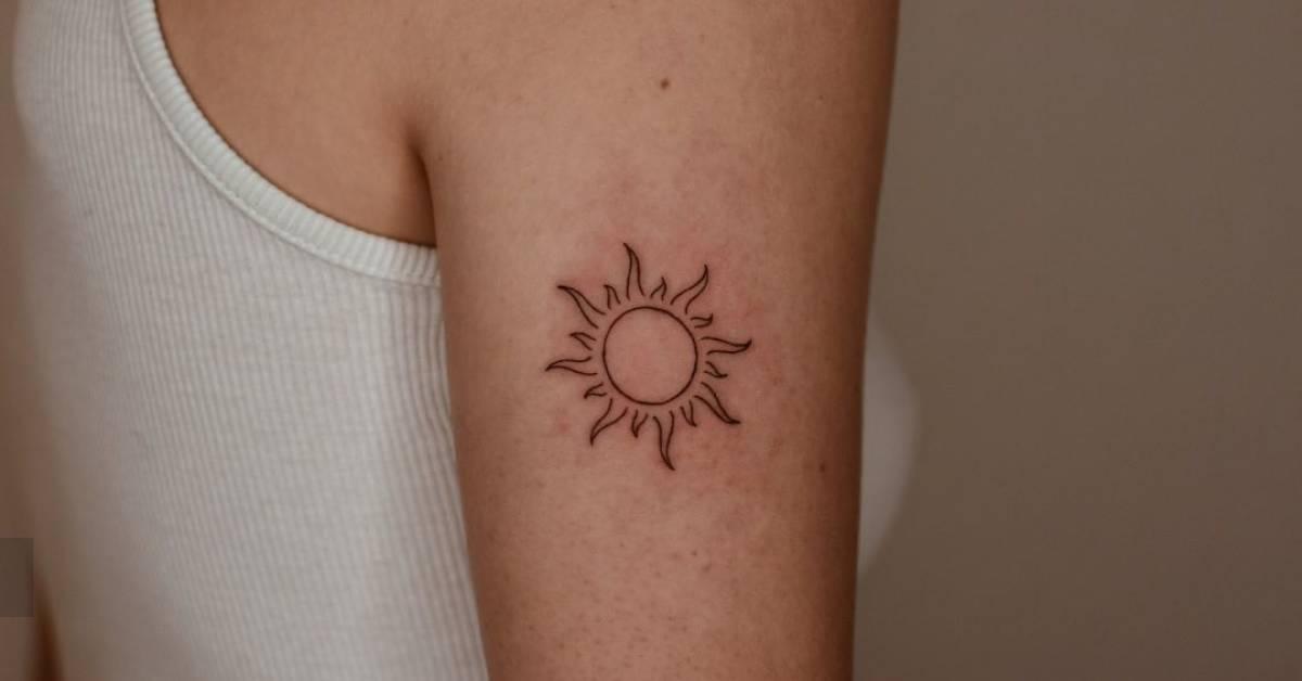 Fine line style sun tattoo placed on the upper arm.
