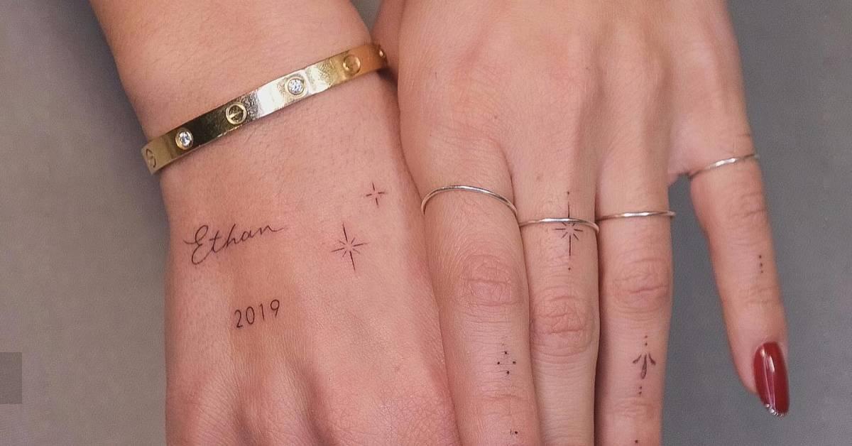 Names "Ethan" and "Achille" lettering tattoo located on