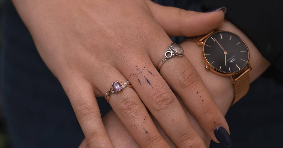 Hand poked ornamental finger composition tattoos.