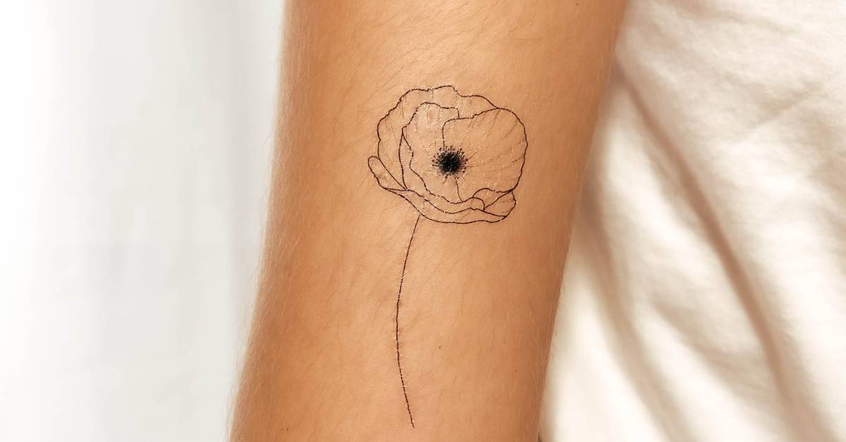 Fine line poppy temporary tattoo located on the tricep.