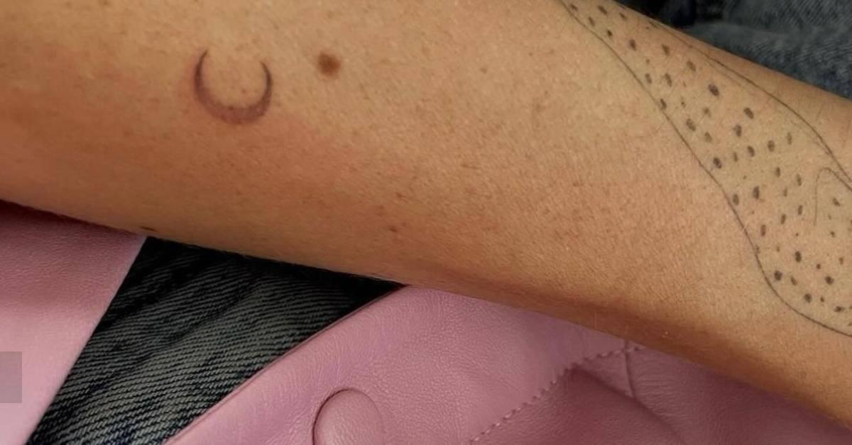 Minimalistic style crescent moon tattoo located on the