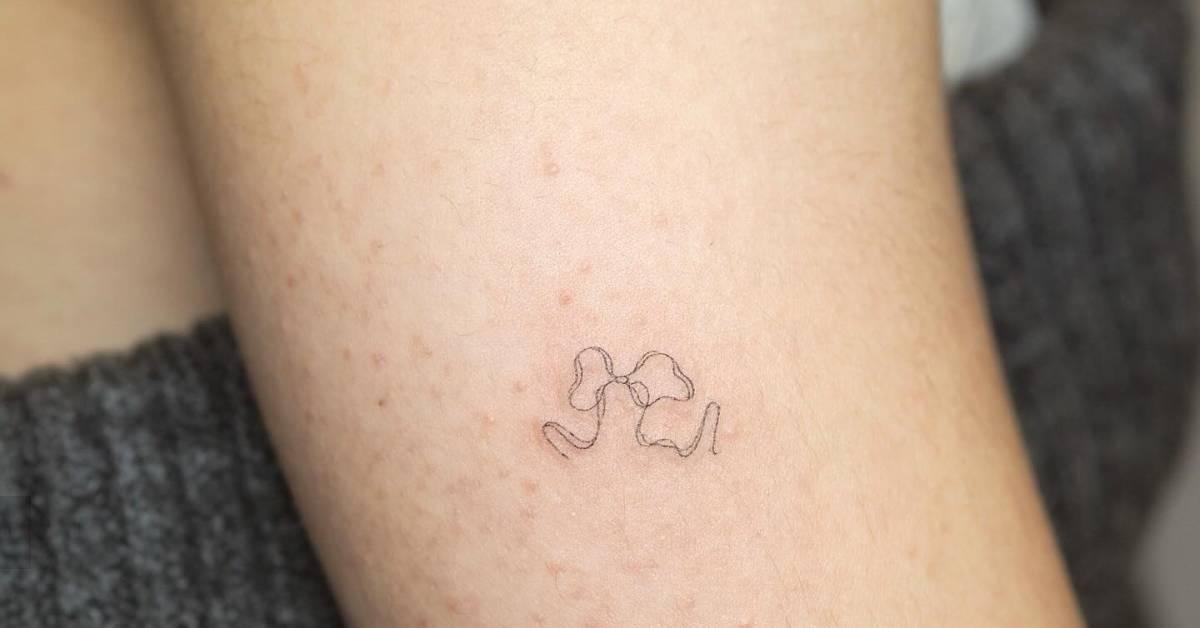 Fine line style ribbon tattoo done on the upper arm.