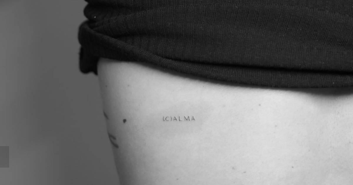 "(C)alma" lettering tattoo located on the back.