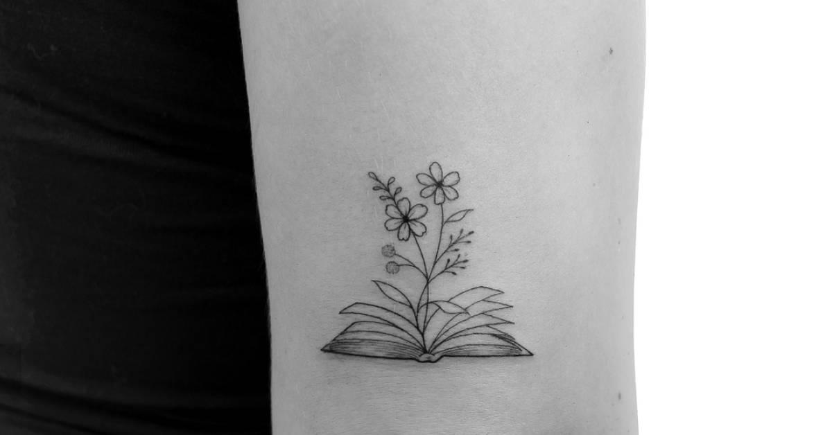 Fine line style flowers and book tattoo located on the