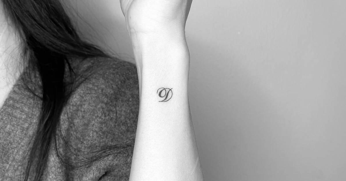 Little letter "D" tattoo located on the wrist.