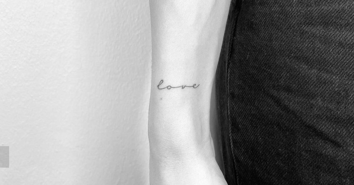 Tattoo of the word "love" handwritten on the wrist.