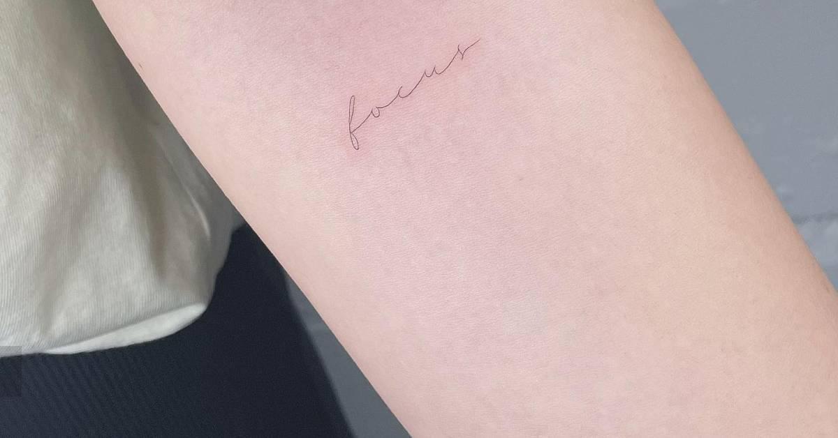 Tattoo of the word "focus" handwritten on the inner