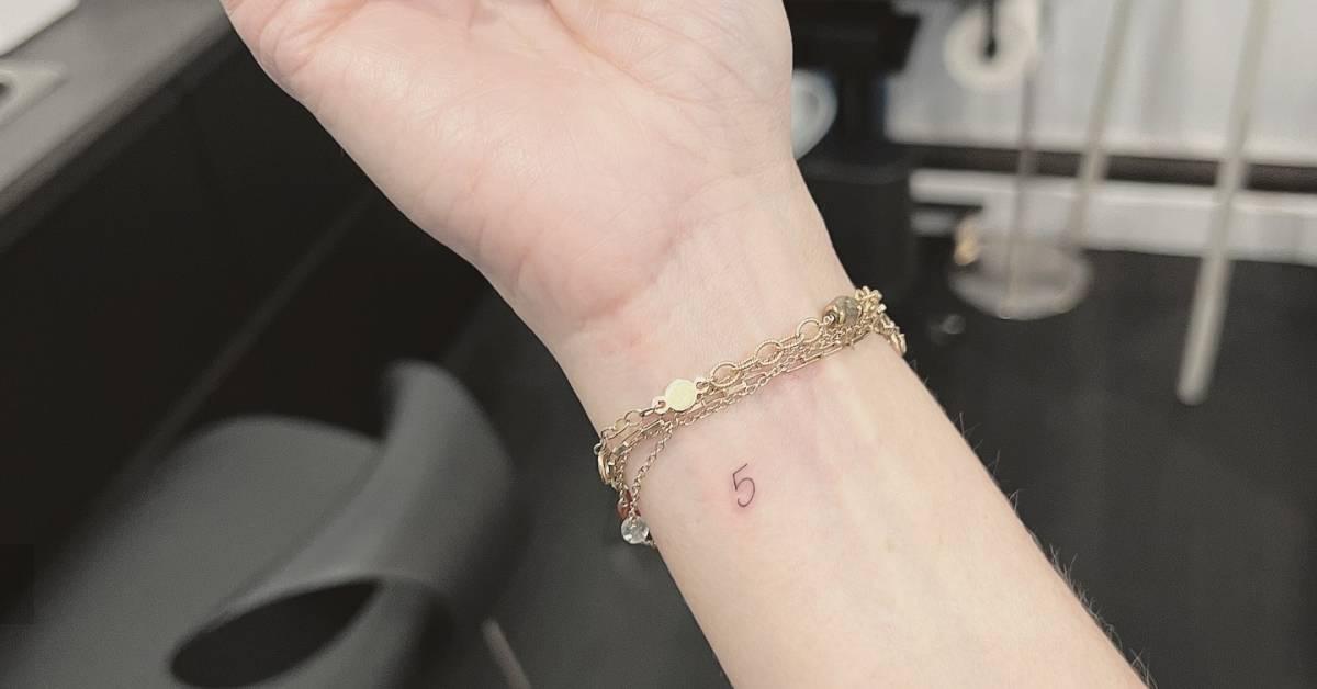 Minimlistic style number "5" tattoo located on the
