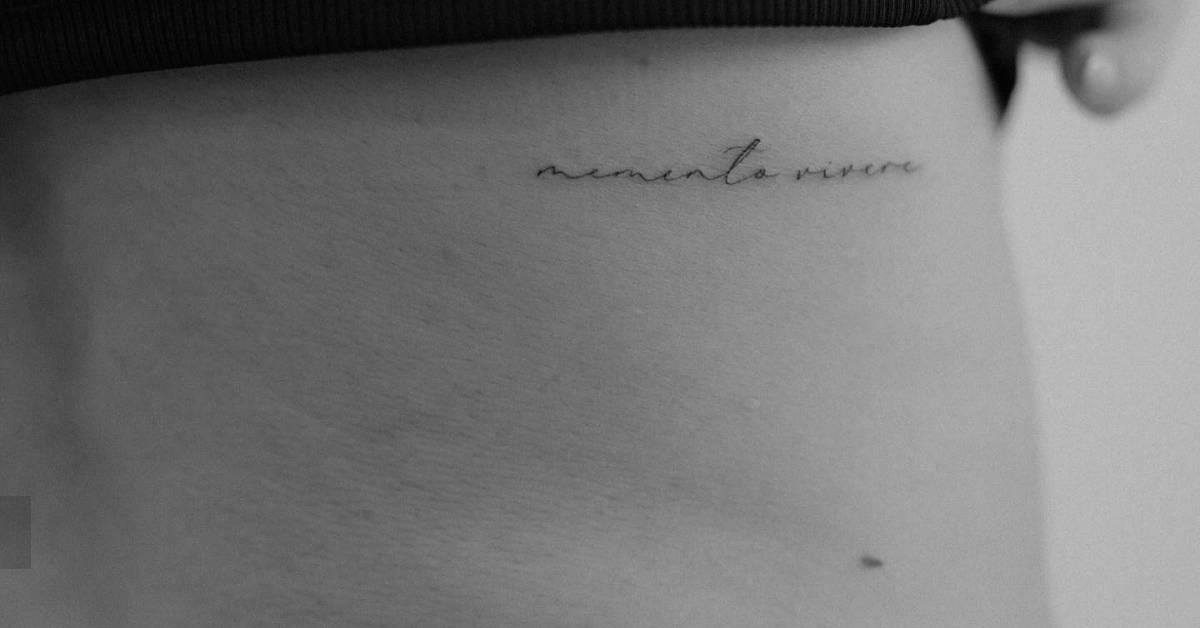 Lettering tattoo that says "memento vivere" handwritten