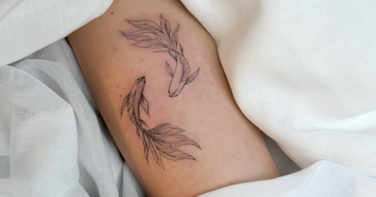 Fine line style two opposite fish tattooed on the inner