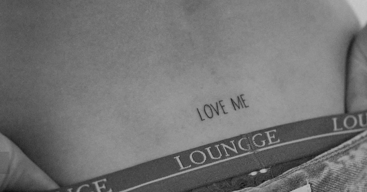 Tattoo that says "love me" located on the lower back.