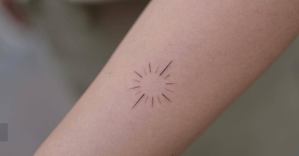 Minimalistic style sun tattooed on the forearm.