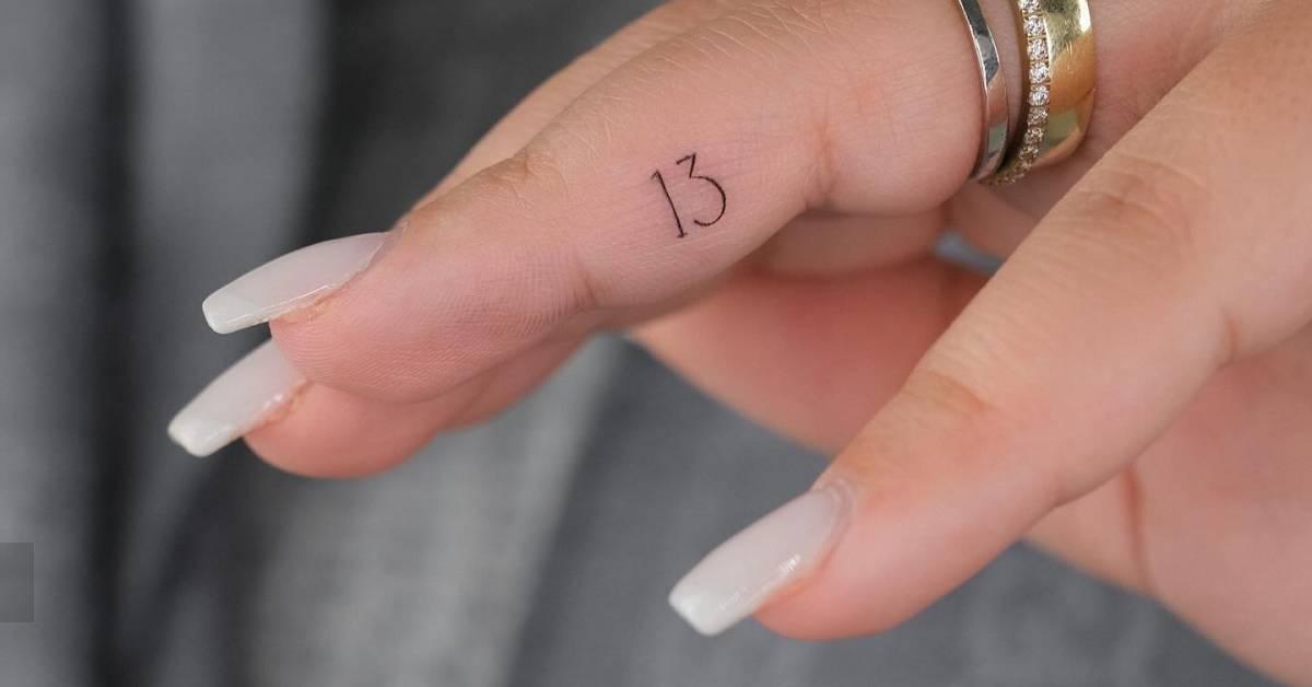 Tiny tattoo of the number "13" placed on the finger.