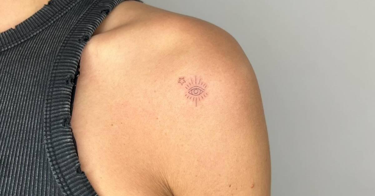 Fine line style evil eye tattoo placed on the shoulder.