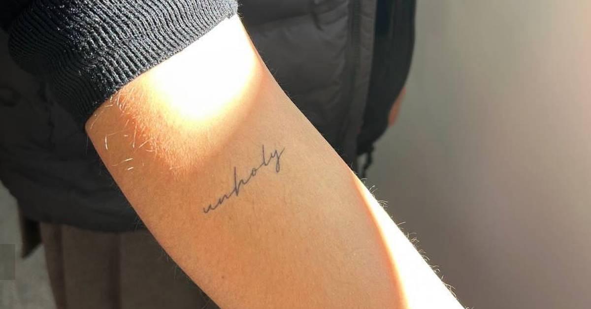 Healed lettering tattoo of the word "unholy" located on