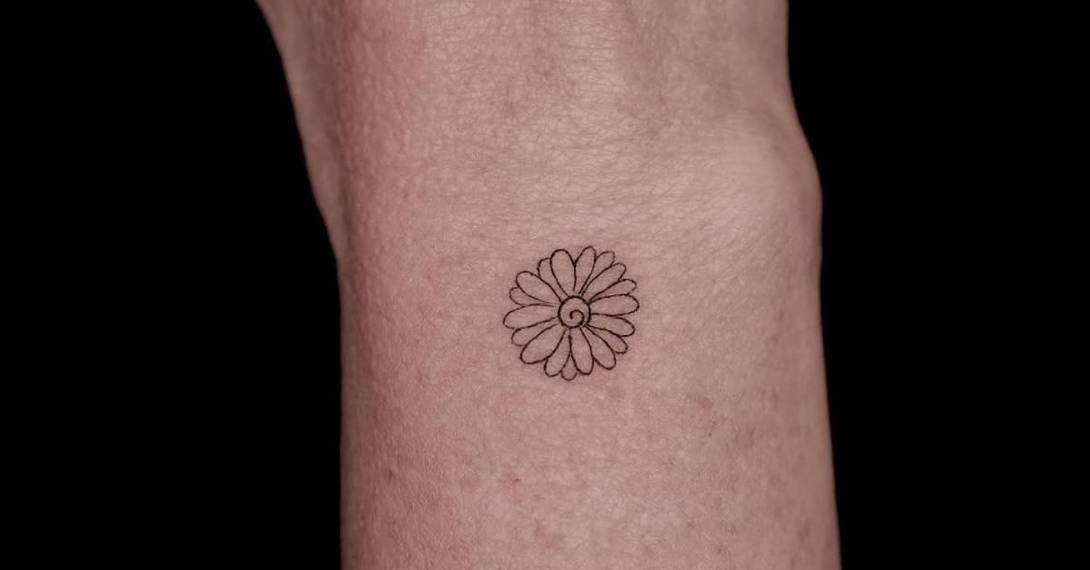 Fine line style daisy flower tattoo located on the