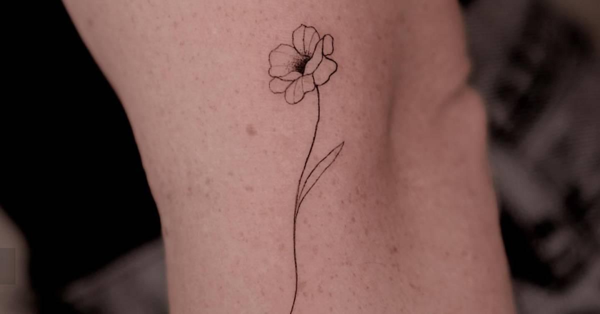 Fine line style poppy flower tattoo located on the