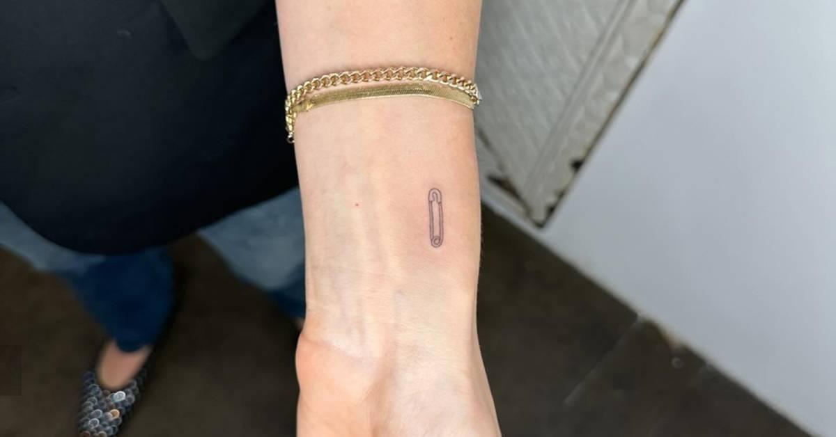 Safety pin tattoo located on the wrist, fine line