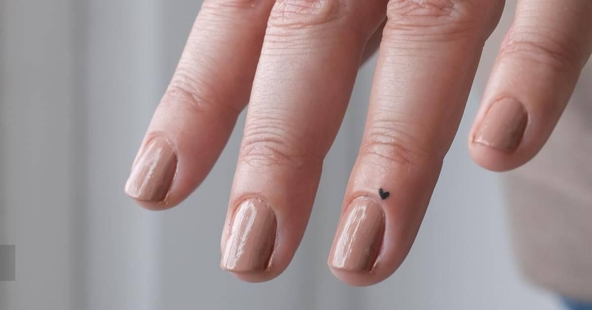 Micro heart tattoo located on the finger, minimalistic