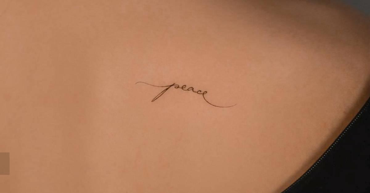 Tattoo of the word "peace" handwritten on the shoulder