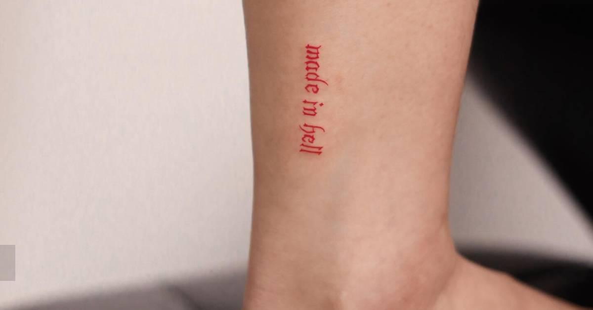 "Made in hell" lettering tattoo in red ink located on