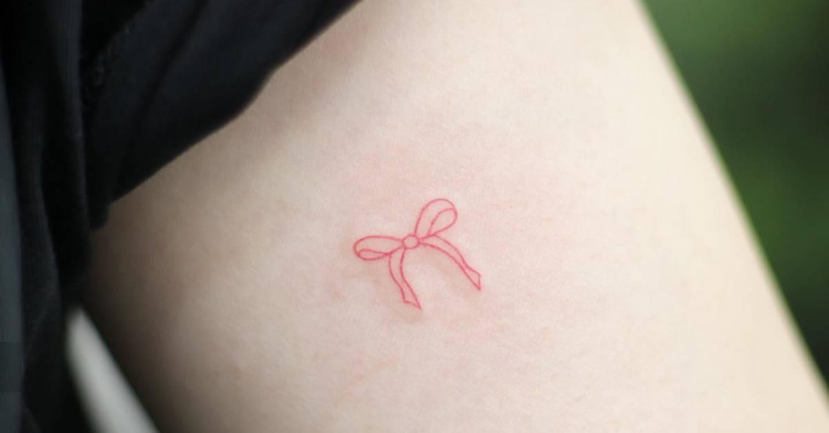 Tiny fine line red ribbon tattoo located on the inner