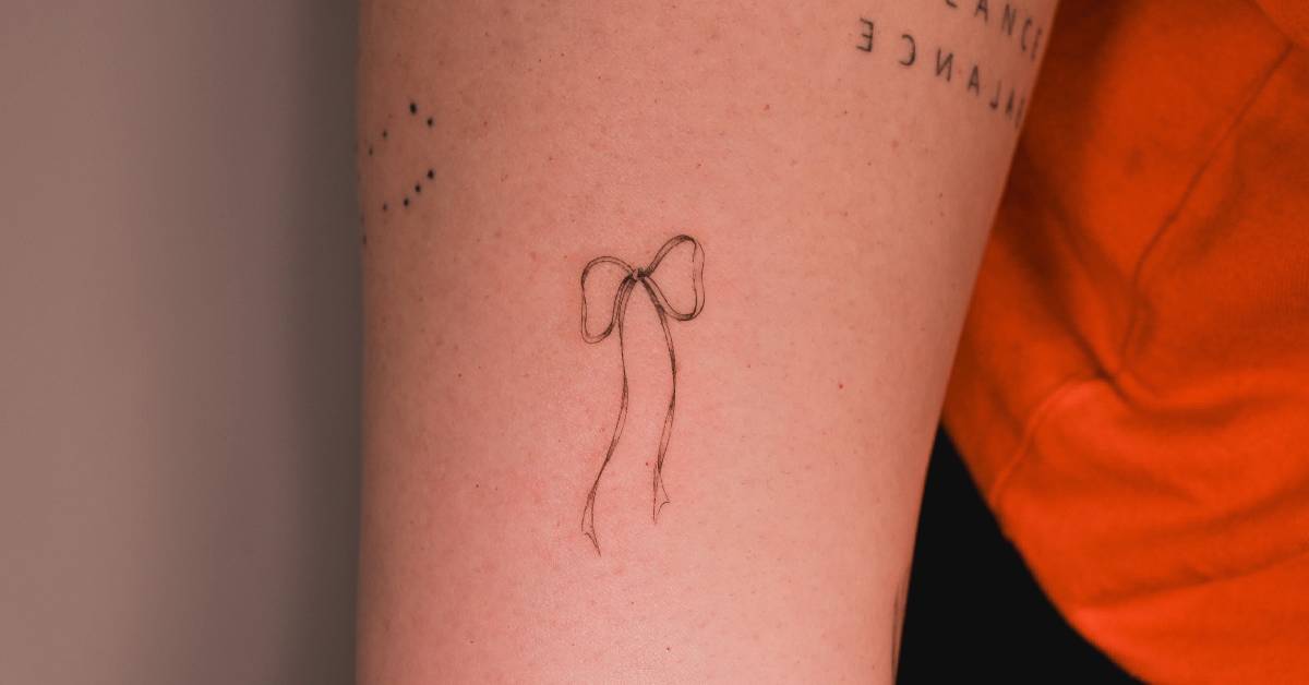 Fine line style ribbon tattoo located on the forearm.