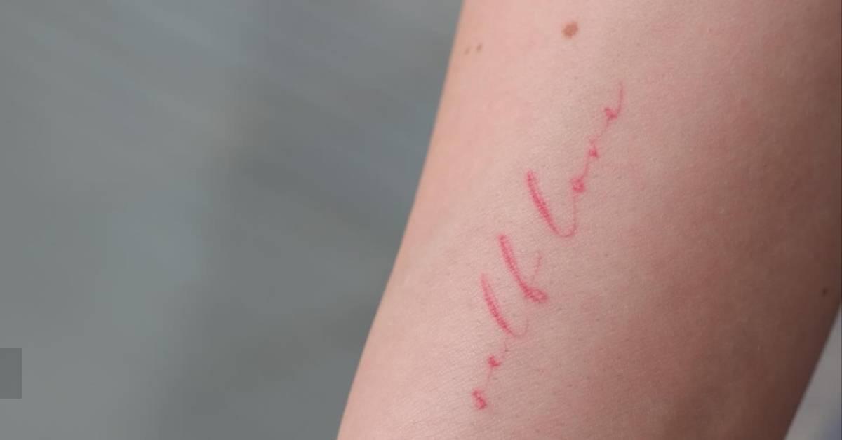 Healed "self love" lettering tattoo in red ink located