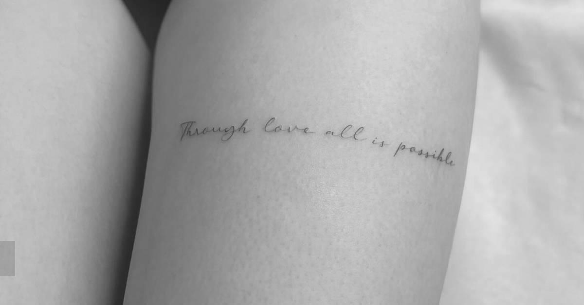 "Through love all is possible" lettering tattoo located