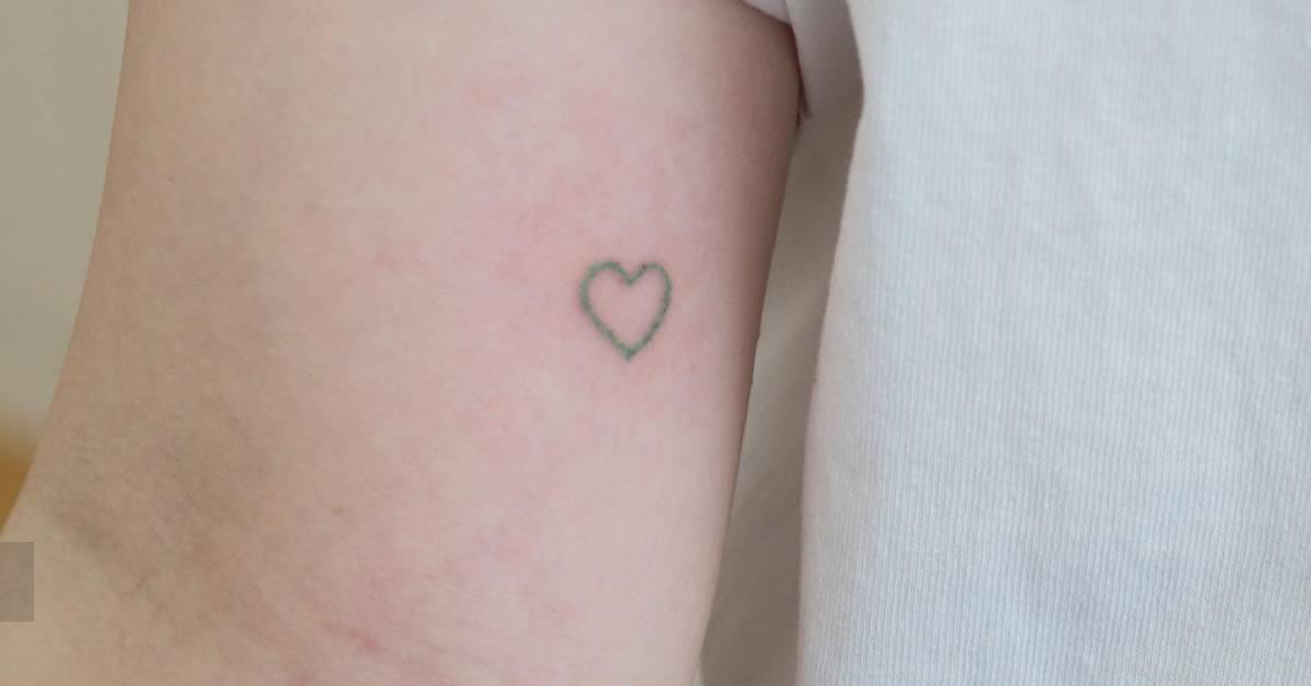 Tiny green heart tattoo located on the inner arm,